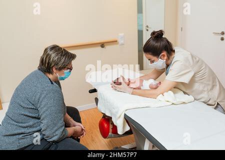 Female physiotherapist doing an extensor tone relaxation on a newborn ...