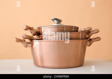 Shiny cooking pots on table against brick background Stock Photo - Alamy
