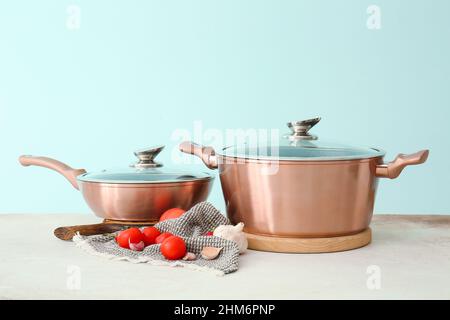 Shiny cooking pots with cutting boards on table against blue background ...