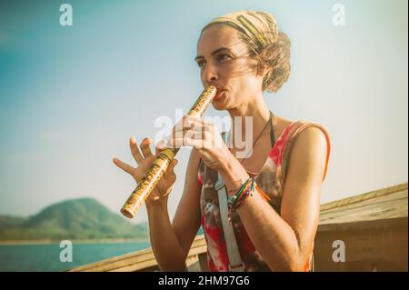 Young woman playing on woodwind wooden flute - ukrainian telenka or ...