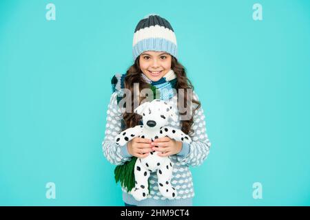 smiling child in knitwear hold toy. teen girl on blue background. happy ...