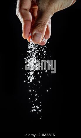 Male hand sprinkling edible salt at black background Stock Photo - Alamy