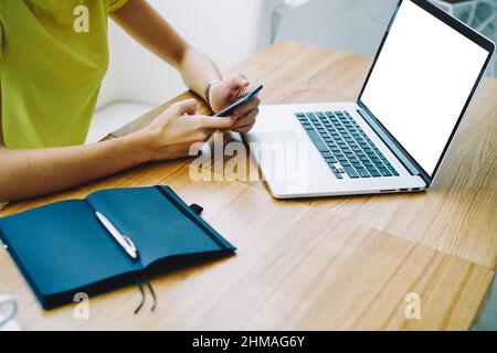 Faceless female freelancer using smartphone and laptop in workspace Stock Photo - Alamy