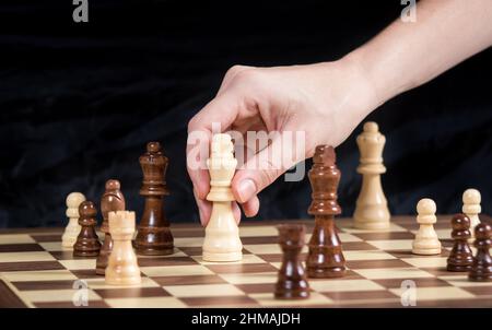Person moving King Chess piece during a game with light background ...
