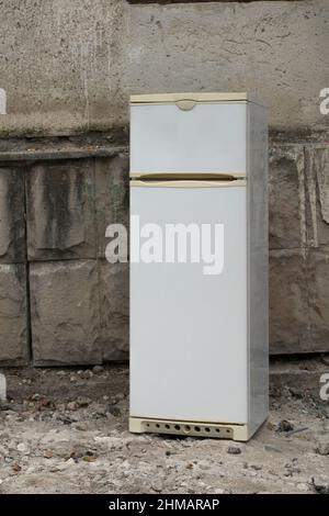 An old rusty refrigerator was thrown away on the street in sun light ...