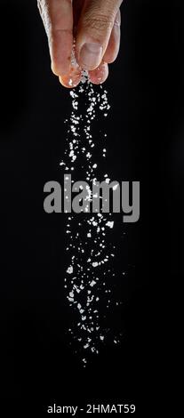 Male hand sprinkling edible salt at black background Stock Photo - Alamy