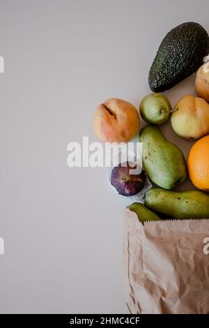 A variety of fruits in a crafted paper bag are lying on the table ...