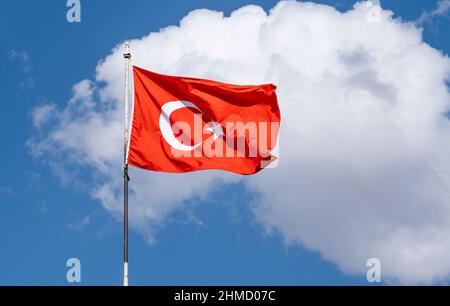 The Turkish national flag waving on a flagpole over the blue waters of ...