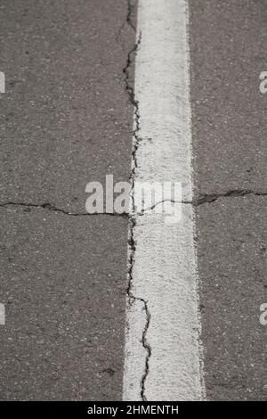 Perspective cracked asphalt road ahead to the mountain. Long straight ...