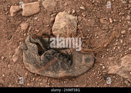 Ailing leather work boot stands on a wall, rotten shoe, shoe wreck ...