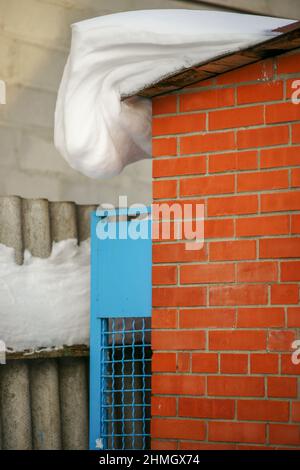 Snowdrift in the form of a wave on the roof of a brick building. Big ...