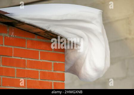 Snowdrift in the form of a wave on the roof of a brick building. Big ...