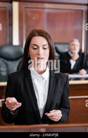 blurred prosecutor talking in court near judge sitting with clenched ...