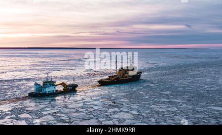 Icebreaker goes on the sea among the blue ice at sunset, aerial view ...