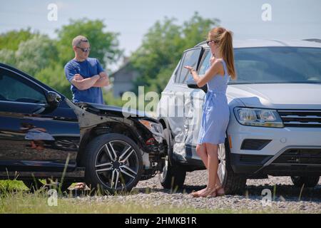 Angry woman and man drivers of heavily damaged vehicles arguing who is ...