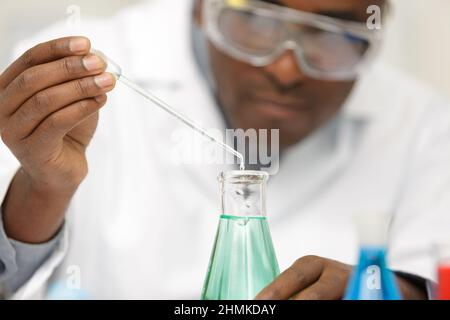 young smiling chemist in googles holding purple liqiud Stock Photo - Alamy