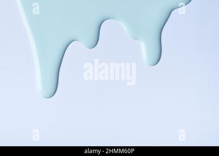 Light blue liquid drops of paint color flow down on isolated white ...