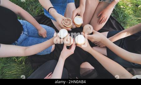 Girls friends join hands with ice cream in waffle cups in a circle ...