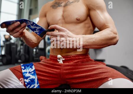 A beautiful athlete boxer, wraps his hands on sports bandages for ...
