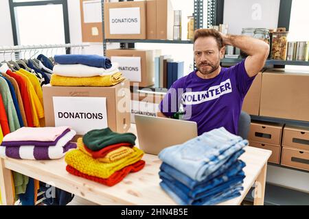 Middle age man wearing volunteer t shirt at donations stand showing ...