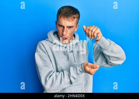 Young caucasian man holding slime depressed and worry for distress ...