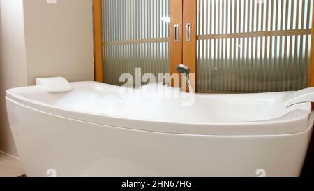 Bathtub with soap suds. Preparing a bath, hot water flows from the tap ...
