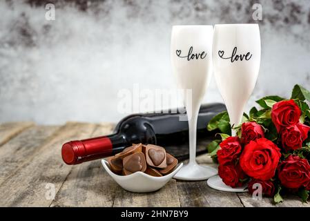 Bottle of wine, chocolate candies, heart, rose flowers and gift on pink ...