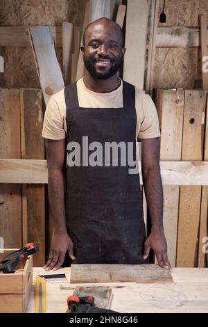 Wood artisan smiling, wearing apron in workshop, working with ...