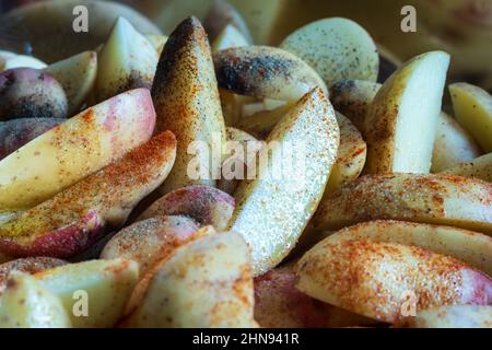 ripe raw cut potatoes wedges spiced on baking tray background closeup ...