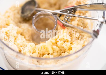 Scooping dough with dough scoop and after rolling in coconut flakes to ...
