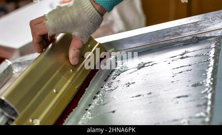 Hand with squeegee for serigraphy silk screen print process at clothes ...