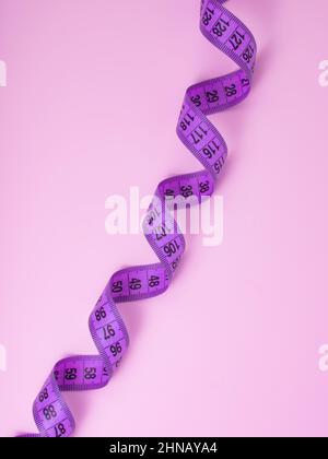 Top view of purple ribbon rolled and pink bow isolated on colored ...