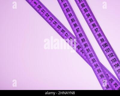 Top view of purple ribbon rolled and pink bow isolated on colored ...