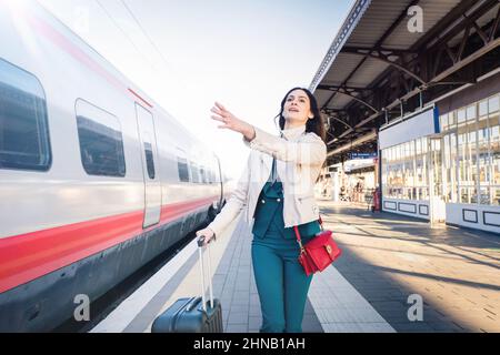 Beautiful girl running and chasing the leaving train in station. Waving ...
