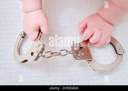 Baby hand and handcuffs, close-up, isolated on a white background ...