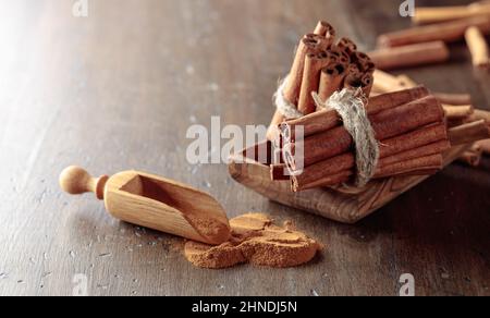 A small dish of cinnamon powder with a bunch of sticks in behind Stock ...