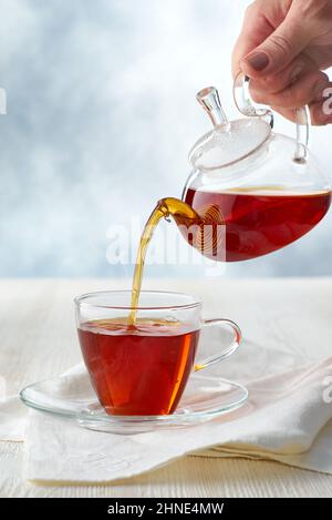 Pouring green tea into a glass teacup filled with ice. Japanese summer ...