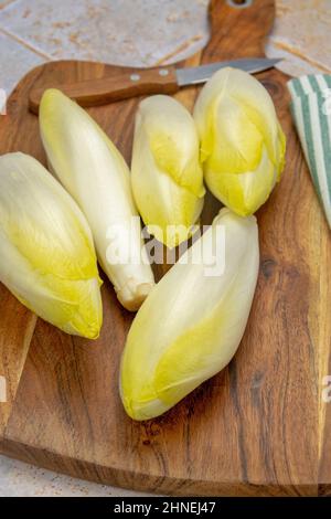 raw endives on a wooden board on a table Stock Photo - Alamy
