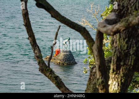 Tangaroa, mythical God of the Seas, statue framed by twisted branches ...
