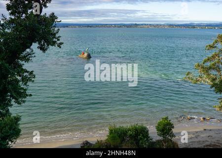 Tangaroa, mythical God of the Seas, statue framed by twisted branches of pohutukawa trees on ...