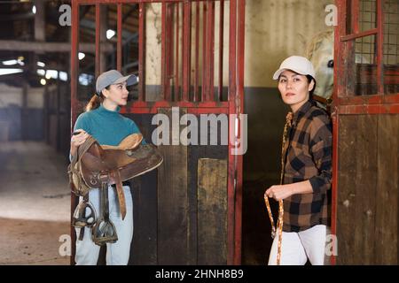 Women ranchers preparing white horse for ride Stock Photo - Alamy