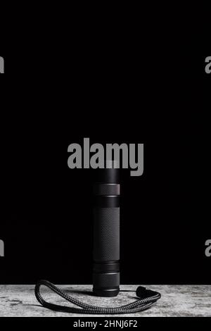 Flashlight stands on a table on a black background with copy space ...