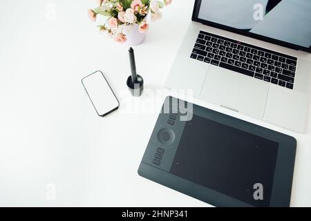 Workspace of professional retoucher. laptop, pot of flower, stylus and ...
