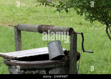 Rustic wooden water well with woodpile of firewood Stock Photo - Alamy