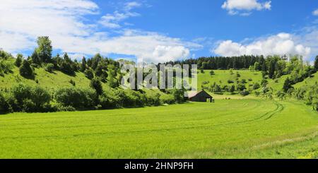 Fields and meadows are enclosed by hills covered with trees Stock Photo ...