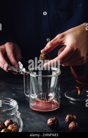 Steeping tea. Putting tea leaves into glass mug Stock Photo - Alamy