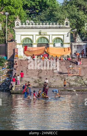 People washing clothes in the Ganga Ganges river by the sewage pipe or ...