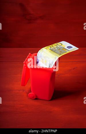 Euro banknote in a garbage can as a symbol for garbage fees, waste of ...