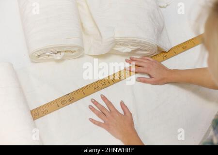 Female hands using wooden tailor ruler to measure cotton fabric ...