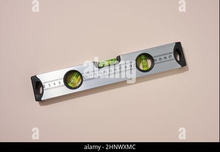 metallic building level on a beige background. Measuring instrument of ...